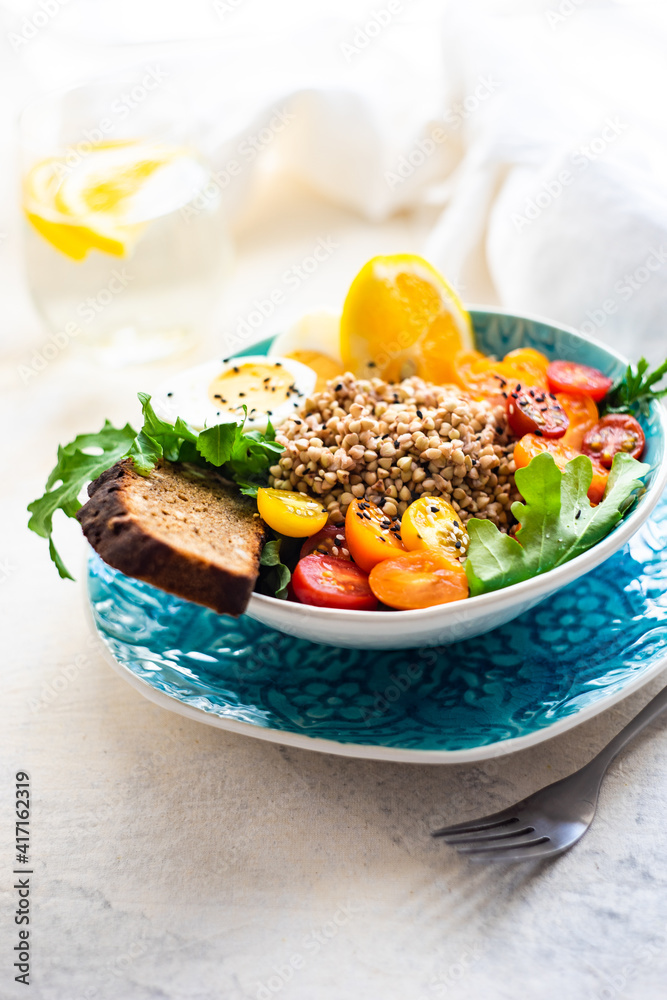 Bowl of buckwheat salad with rocket, tomato, lettuce, hard boiled egg ...