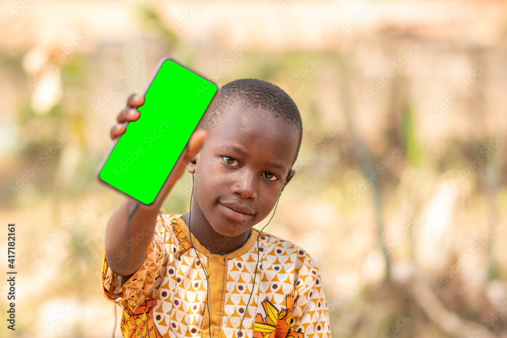 african kid shows the screen of a phone towards the camera, phone has ...
