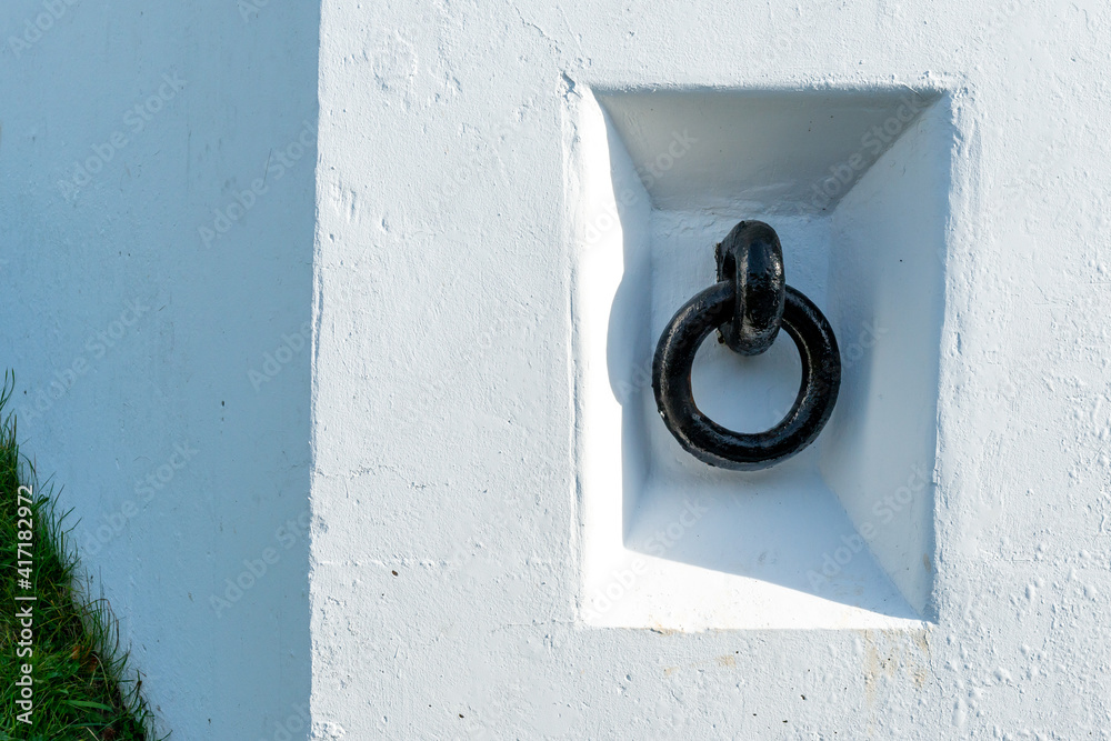 A thick black cast iron or wrought iron ring anchored in a wide white ...