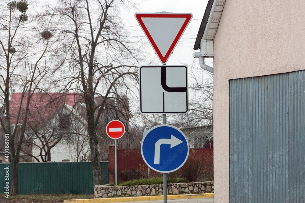 three road signs give way and direction indicators on a pole on the ...