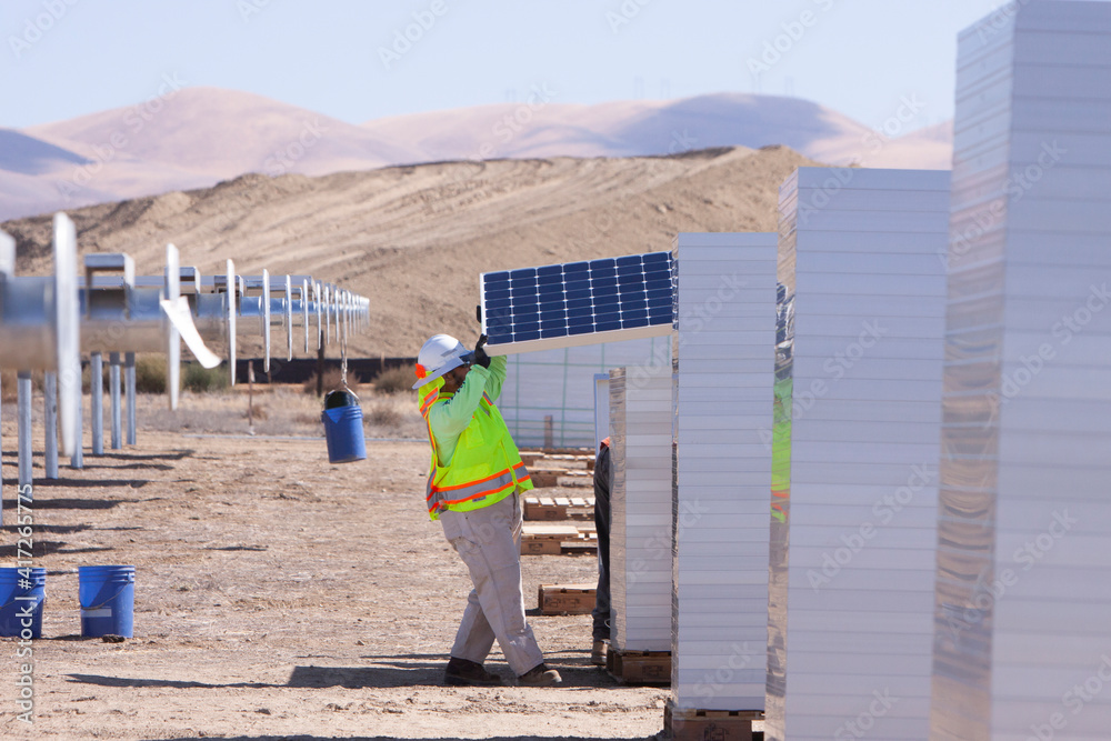 Male workers on construction site at solar farm pulling solar panel off ...
