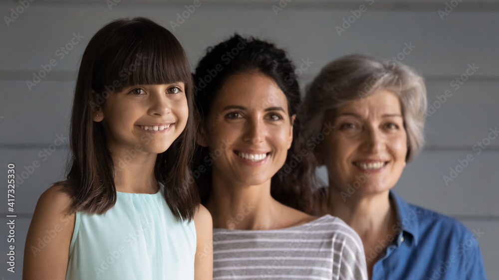 Smiling three generations of Hispanic women look in distance thinking ...