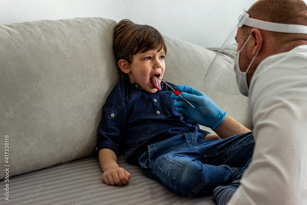 Photo of a cute boy having his mouth swab sample taken by the ...