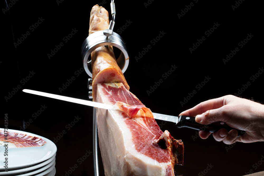 jamón serrano iberico de bellota, mano con cuchillo cortando jamón ...