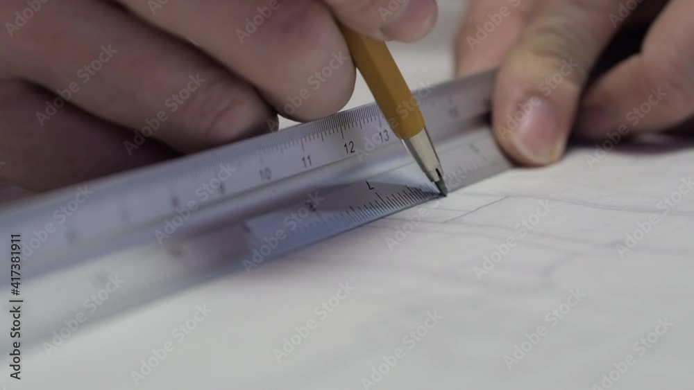 A graphic designer making a line with a ruler over a blueprint on the ...
