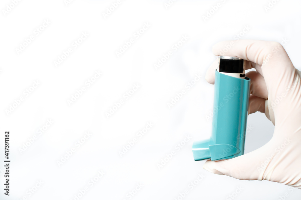A woman's hand in a glove, the doctor's hand holds an asthma inhaler ...