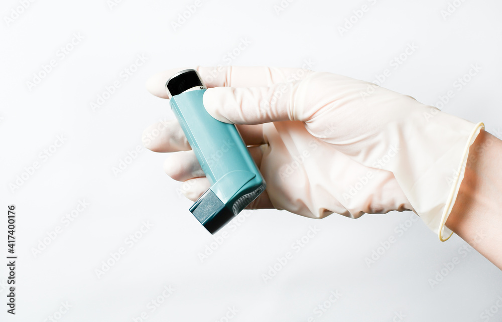 A woman's hand in a glove, the doctor's hand holds an asthma inhaler ...