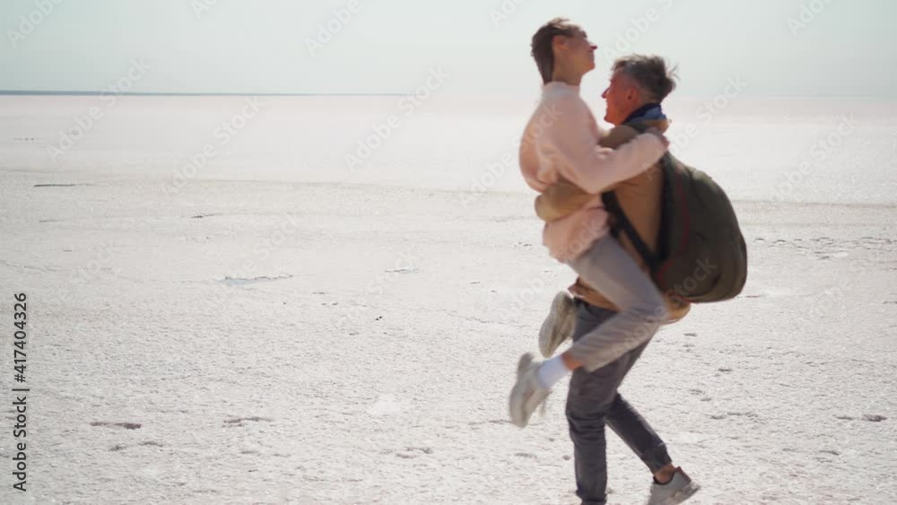 happy cheerful attractive woman jumping on man, hugging and kissing him ...