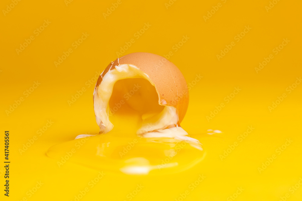 Yellow yolk spilling out of dropped egg mixing with the yellow surface ...