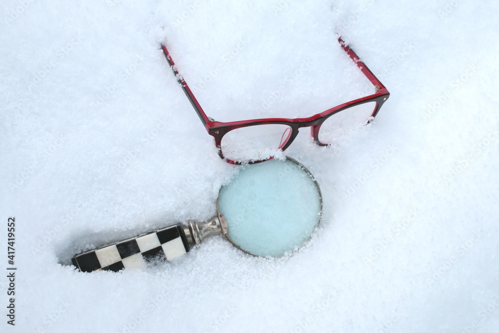 Snow scene close up of glass red spectacles and vintage magnifying ...