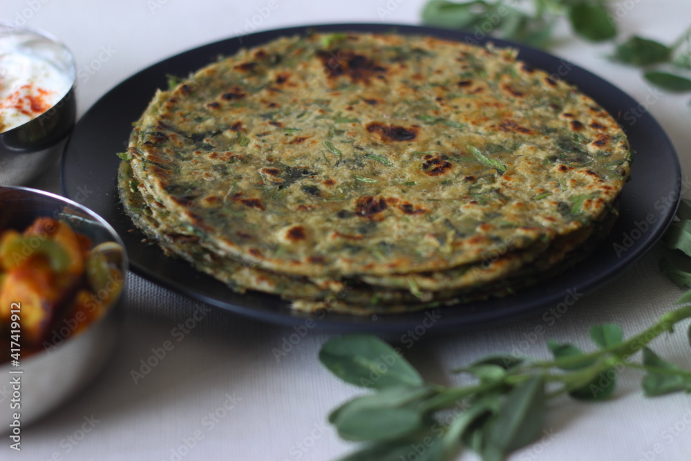 Whole wheat methi thepla rolls with paneer capsicum filling and a bowl ...