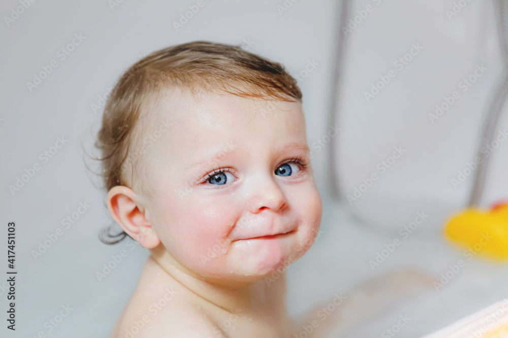 Cute adorable baby child taking bath in bathtub at home. Happy healthy ...