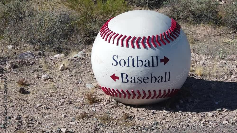 A large baseball is used as a directional sign for baseball and ...