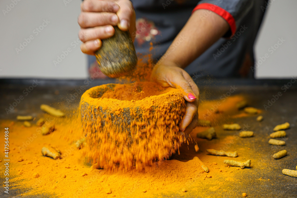 Woman hand powdering Indian spices turmeric powder splash explosion ...