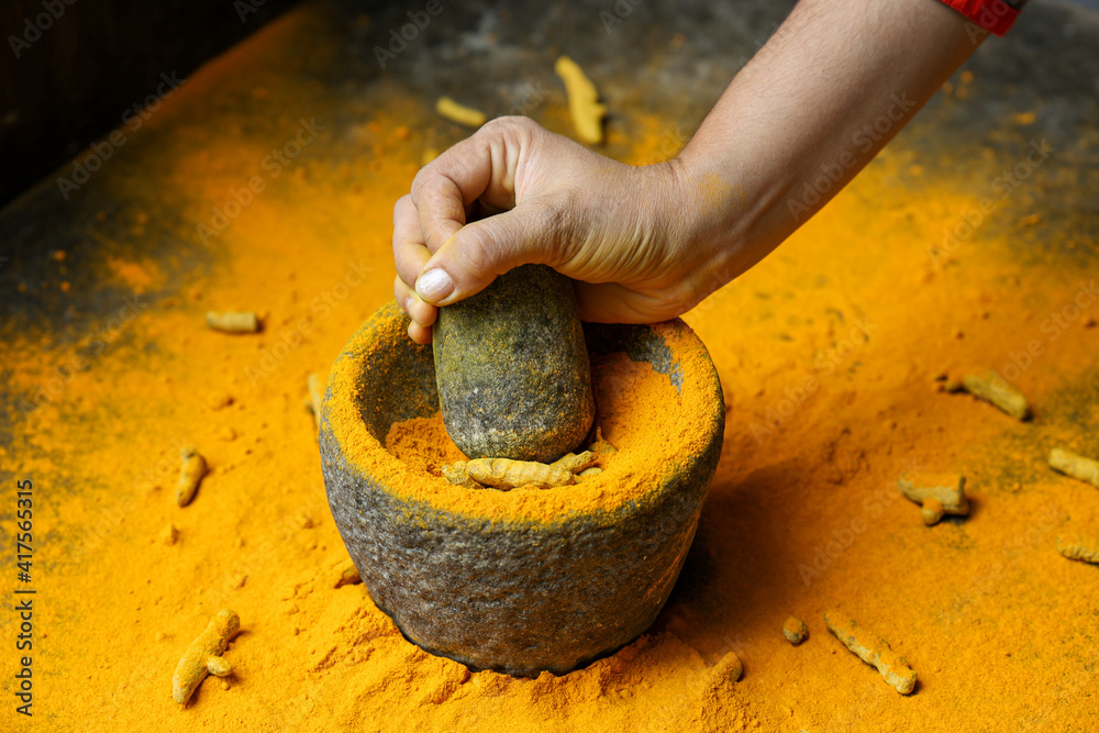 Woman hand powdering Indian spices turmeric powder stone mortar Kerala ...