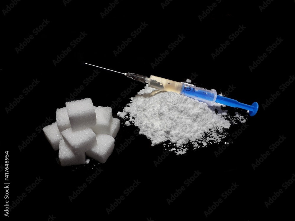 Injection syringe on cocaine drug powder pile and lump sugar cubes on ...