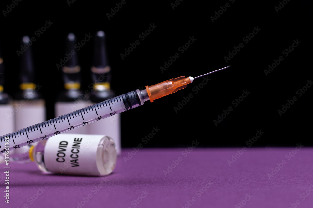 On an isolated black and purple or purple background, a bottle of covid ...