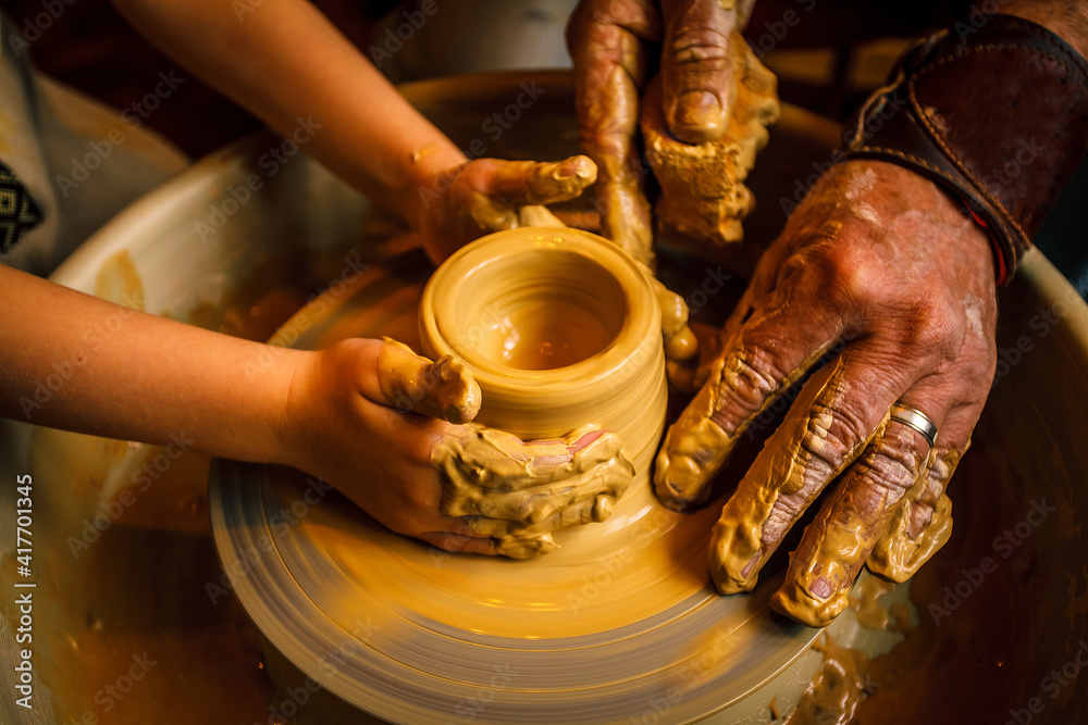 A close-up of the hand of a male potter who teaches his pupil, a child ...