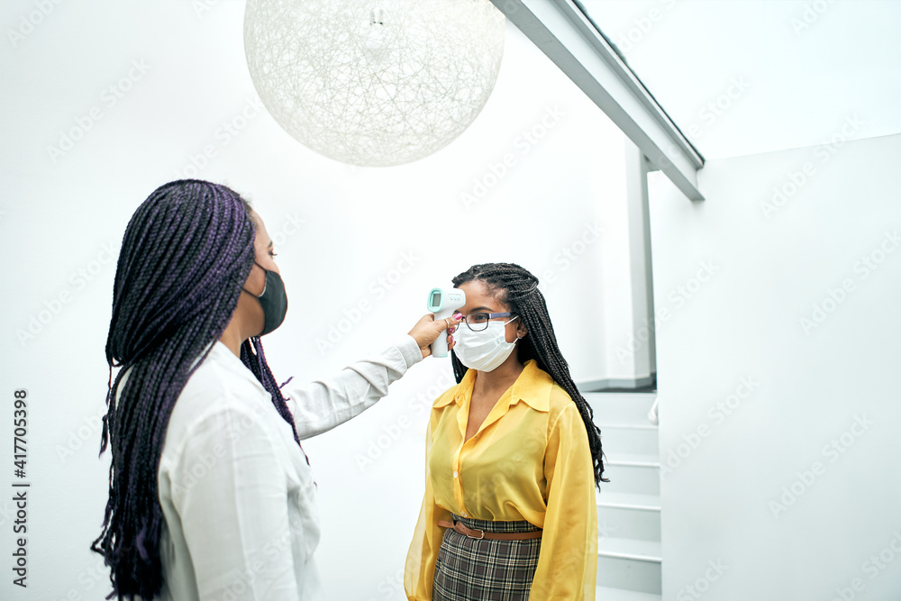 Checking the temperature at the office reception desk before going to ...