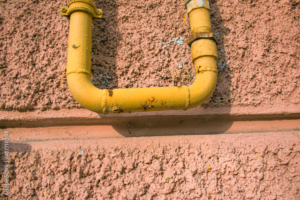 A yellow gas pipe with a coupler runs along the facade of a multi-story ...