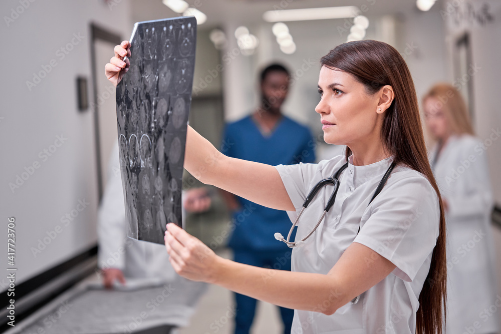 side view on brunette woman looking at x-ray radiography of brain ...