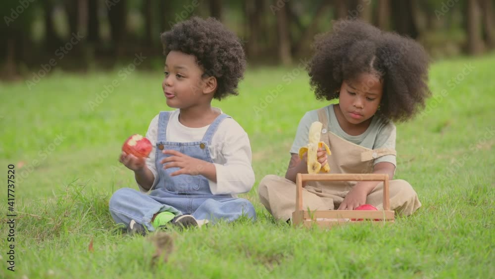 Two african american dark skin child boy and girl sitting and eating ...