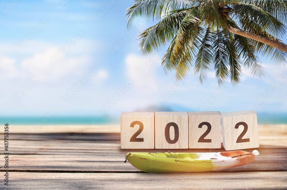 2022 written on wooden cube with boat kayak on planks on tropical beach ...