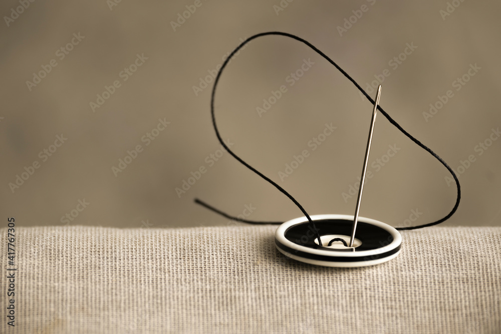 The black and white button is sewn with a sewing needle and black ...