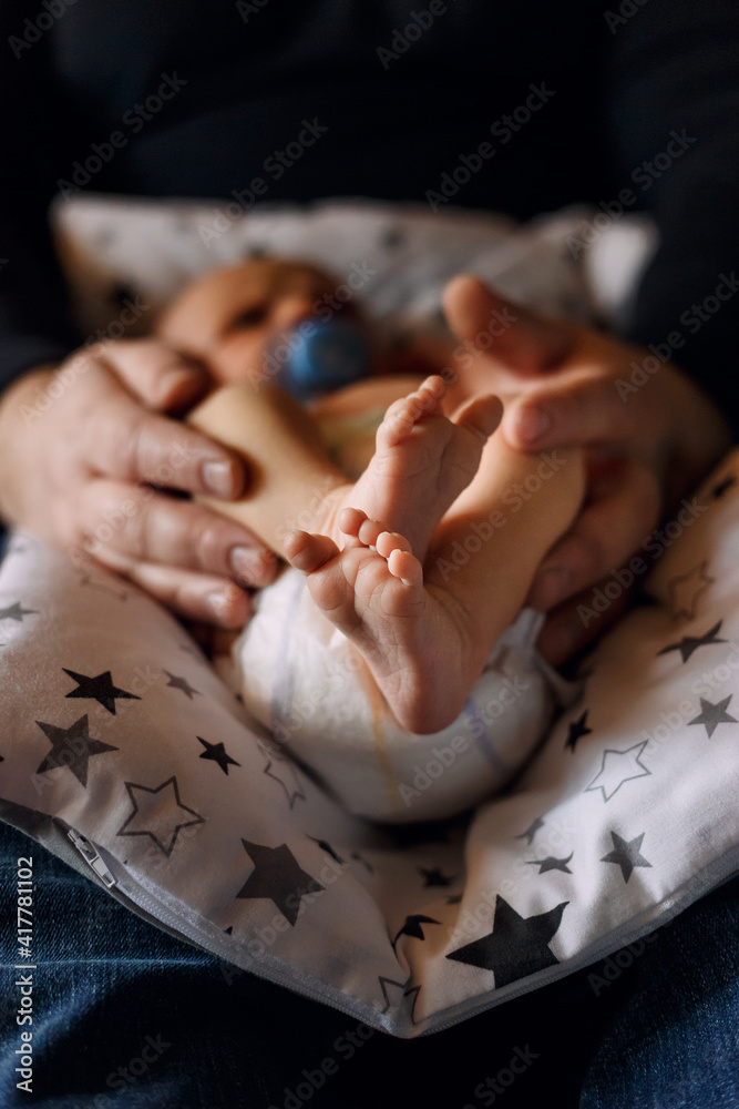 Feet of the newborn in the palms of the dad. Little baby fingers and ...
