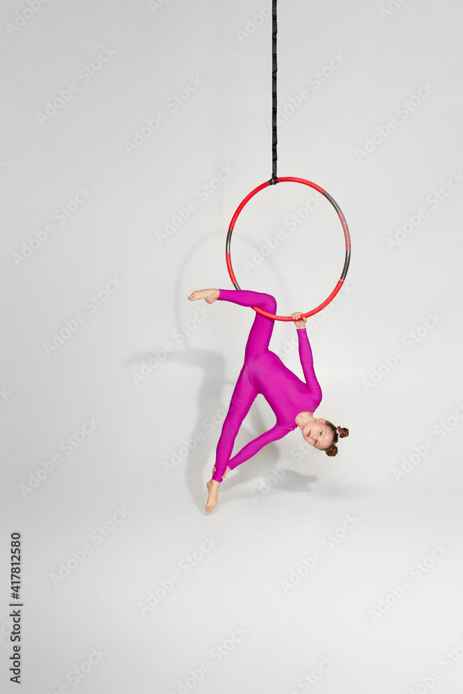 little child girl gymnast in pink sportwear shows an acrobatic ...