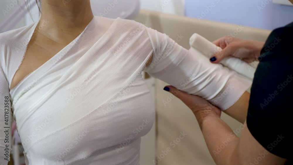 Hands of the master wrap the patient's female body with an elastic ...