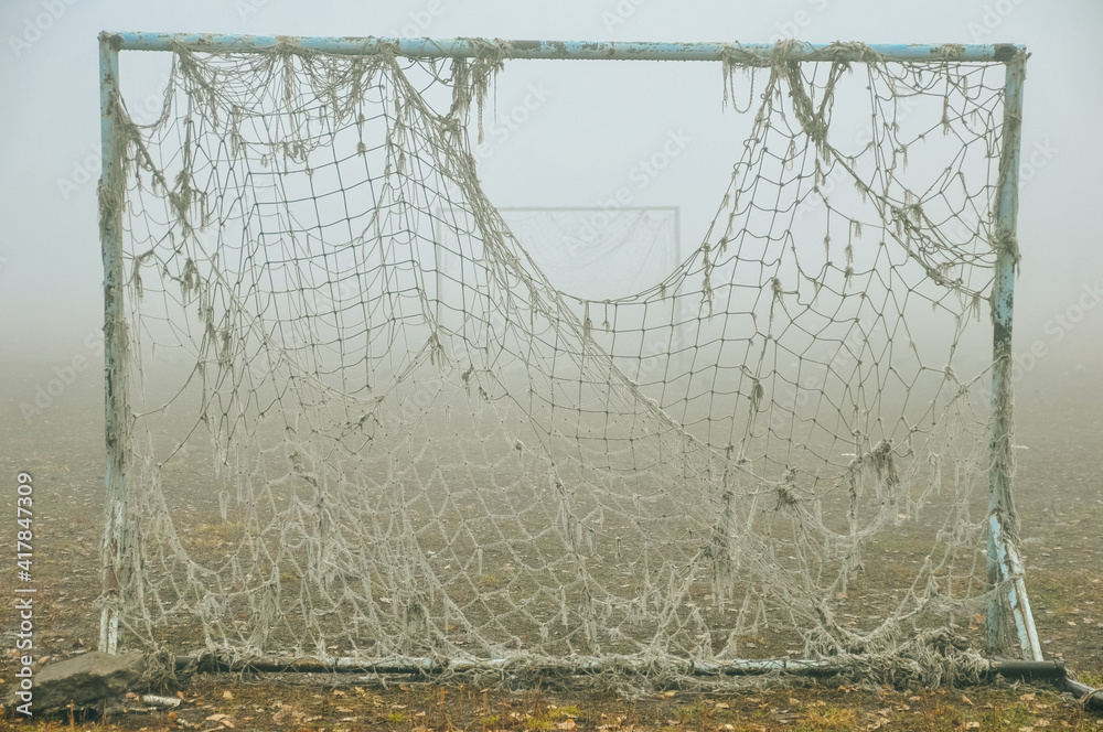 Old empty abandoned football field and gate with a tangled net in a ...