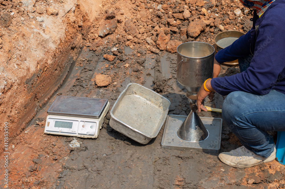 Worker using equipment for testing laboratory field density test sand ...