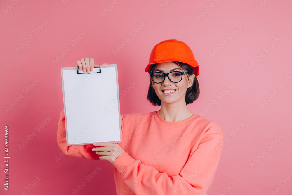Smiling woman worker builder hold white sign board blank against pink ...