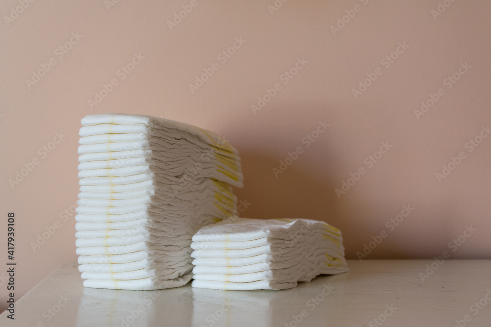 Two uneven stacks of diapers on a dresser in a pink baby girl nursery ...