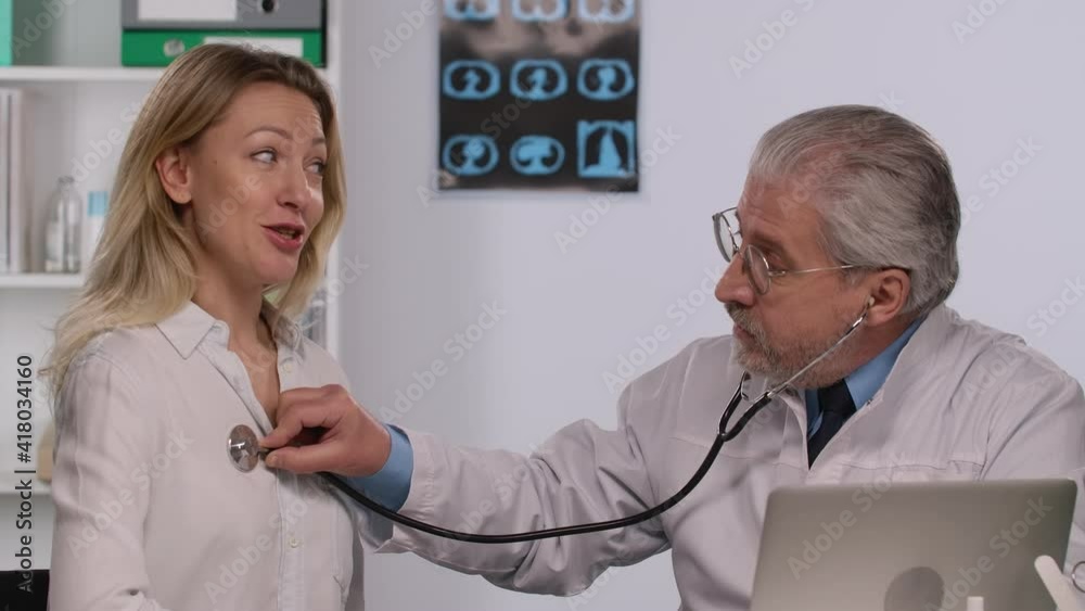 Family medicine doctor examines a woman patient with a stethoscope ...