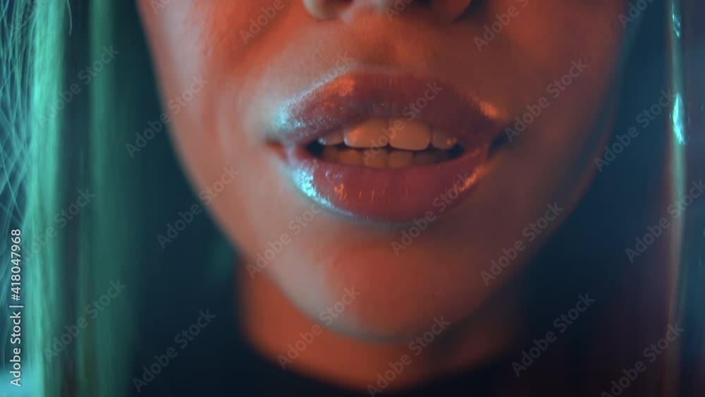 girl's mouth close up, moving her lips and talking in neon lights. Soft ...