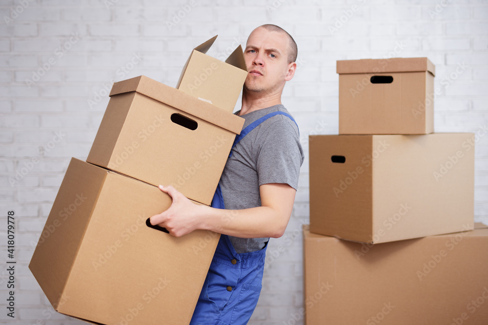 hard work concept - tired man holding many boxes in hands over brick ...