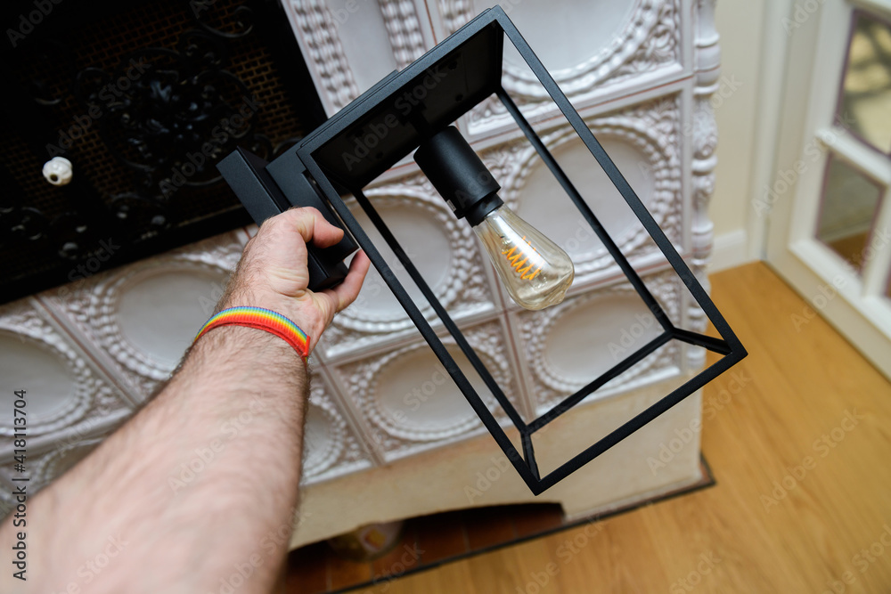 Male hand looking at vintage filament light bulb on box lantern wall ...