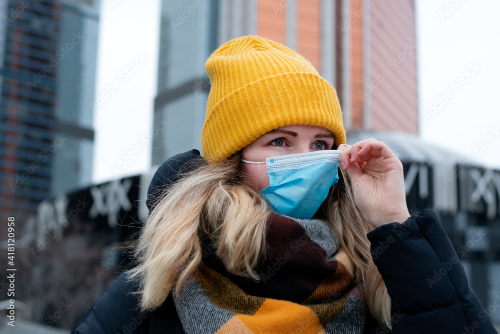 Young woman is putting on a face mask before entering a public space ...