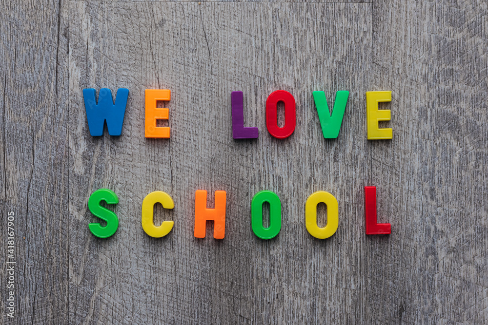 Top down shot of the sentence "We love school" written in single letter ...