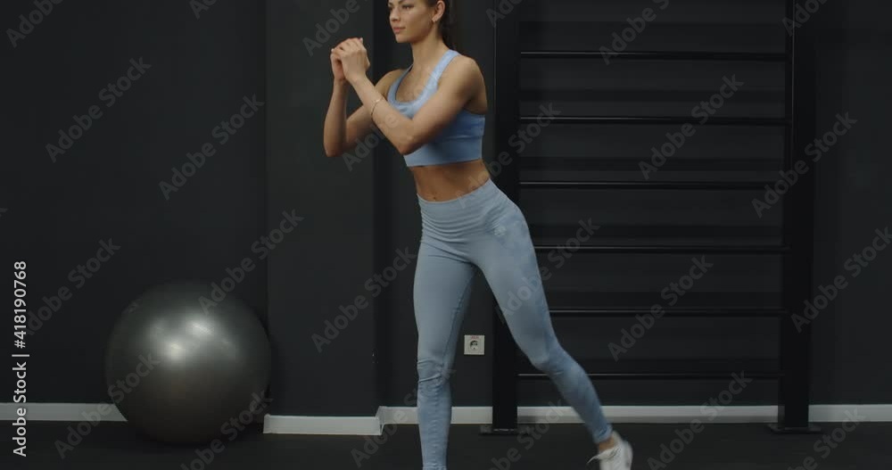 Young slim sportswoman doing squat exercises, working on the lower legs ...
