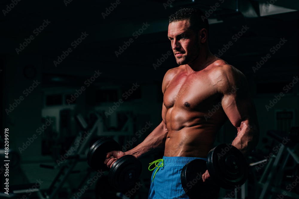 Strong man with dumbbells in gym. Bodybuilder training biceps by ...