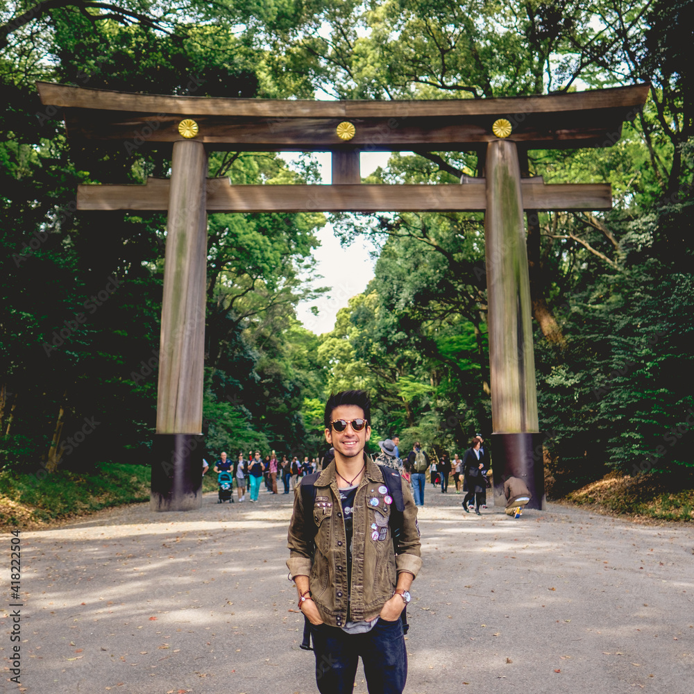 Happy smiling traveler with the great torii gate of the Meiji Shrine at ...