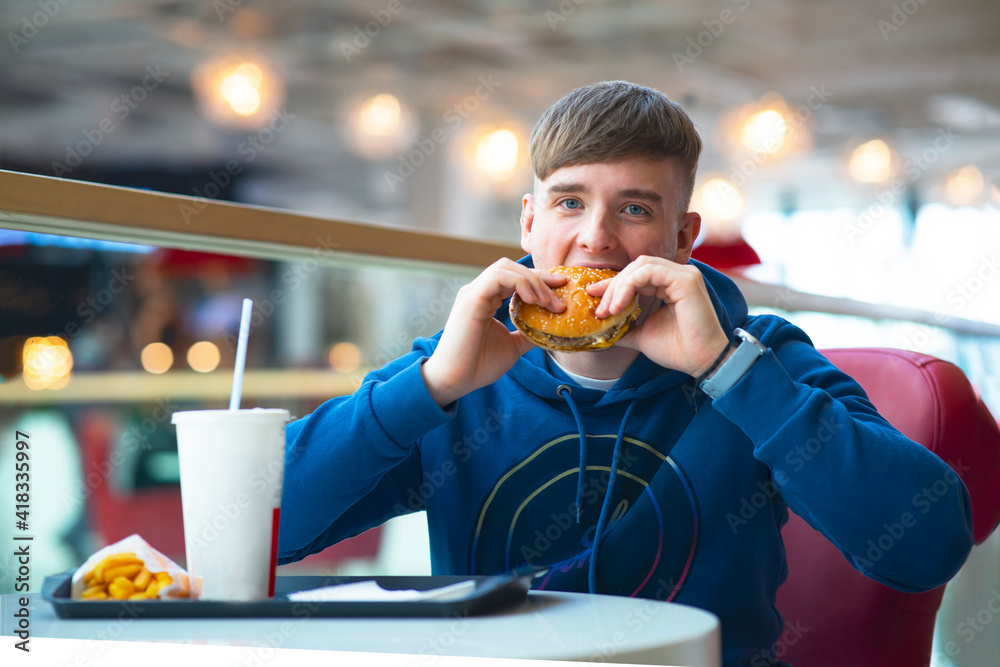 Foto de Young guy eats on a food court, fast food. The man eats a ...