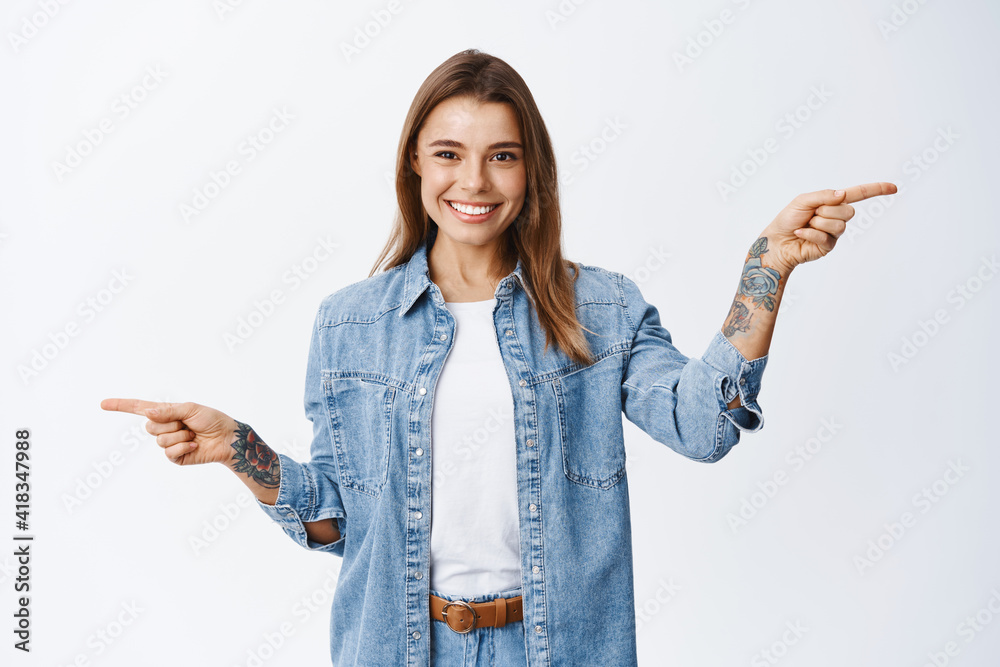Confident smiling woman staring at camera, pointing sideways at left ...