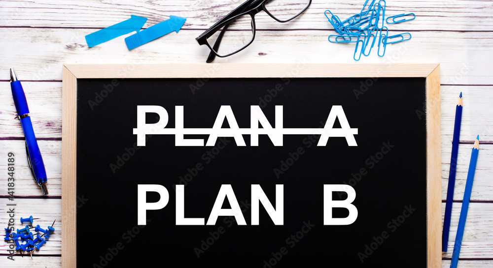 PLAN B written on a black note-board next to blue paper clips, pencils ...