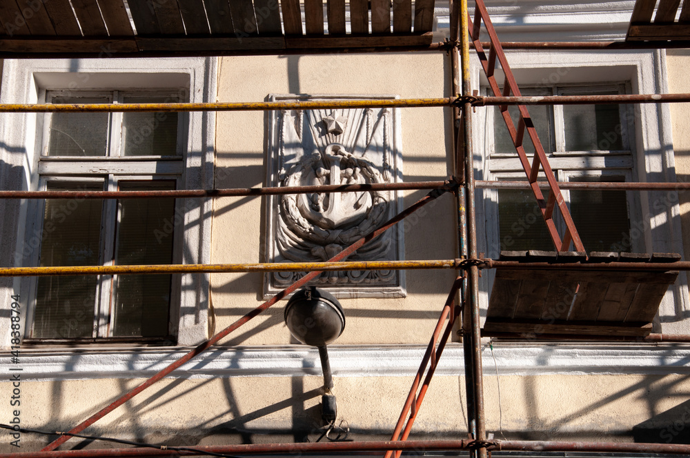 Rusty metal scaffolding in front of historic building wall with ornate ...