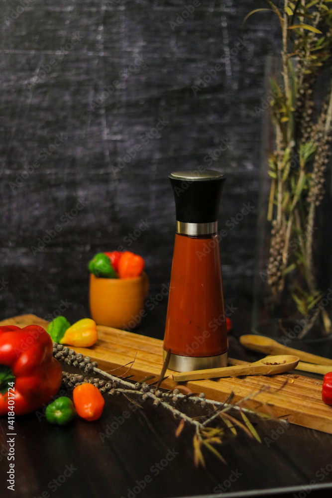 Sesión de fotos para botella de salsa roja picante junto a pimentones y ...