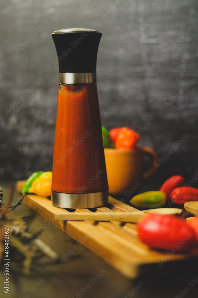 Sesión de fotos para botella de salsa roja picante junto a pimentones y ...
